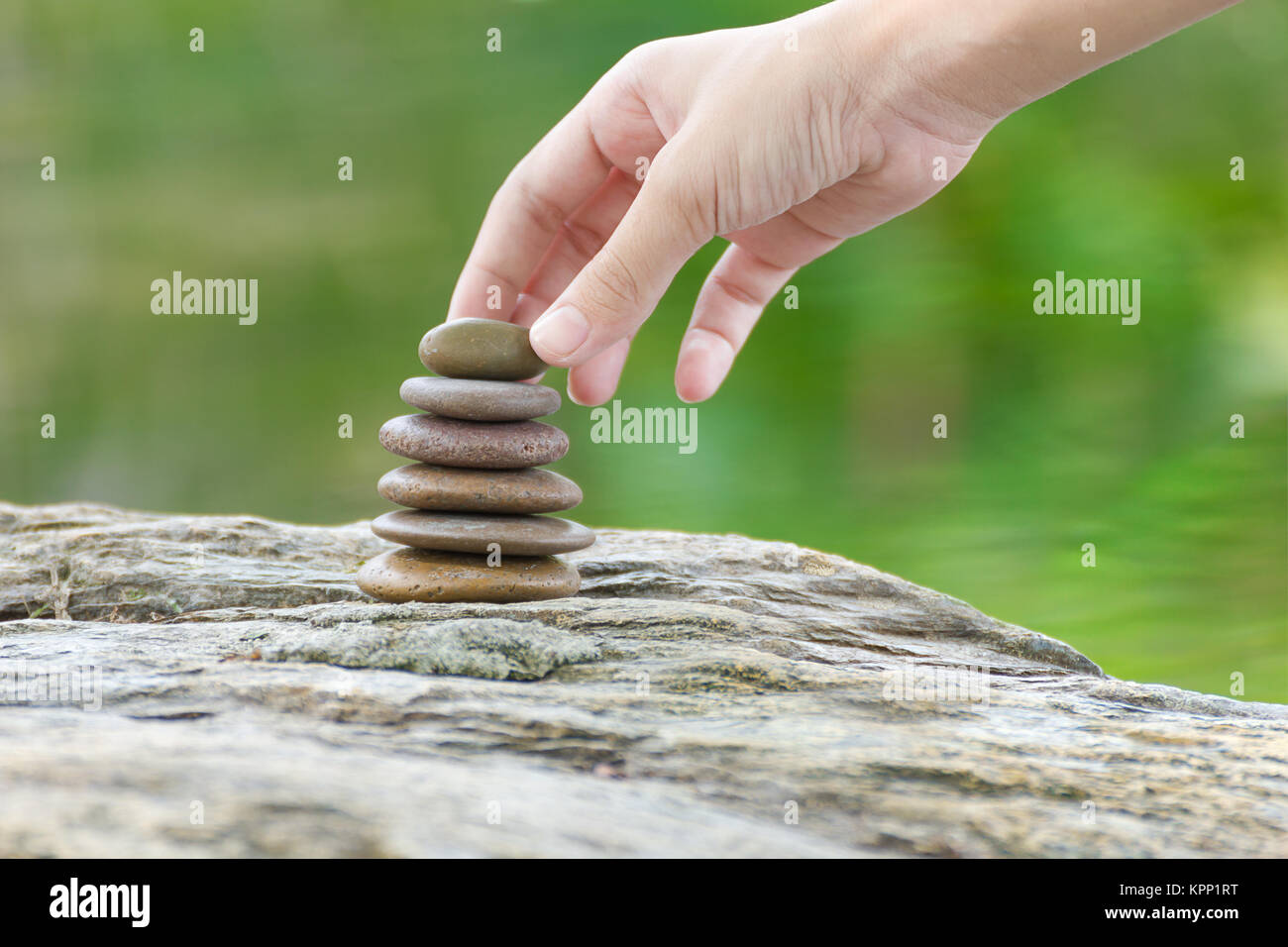 Hand put stone building a pile of zen stones Stock Photo - Alamy