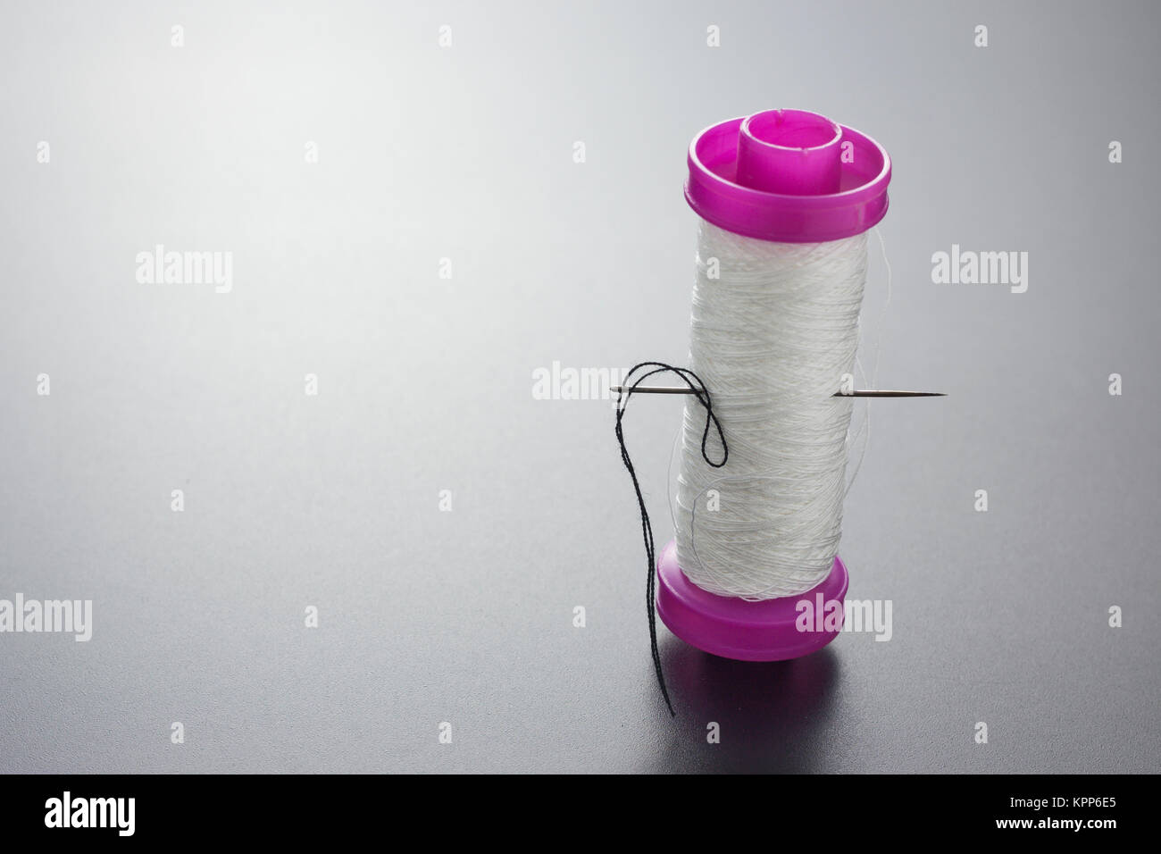Bobbin thread with white sewing needle isolated on gray Stock Photo - Alamy