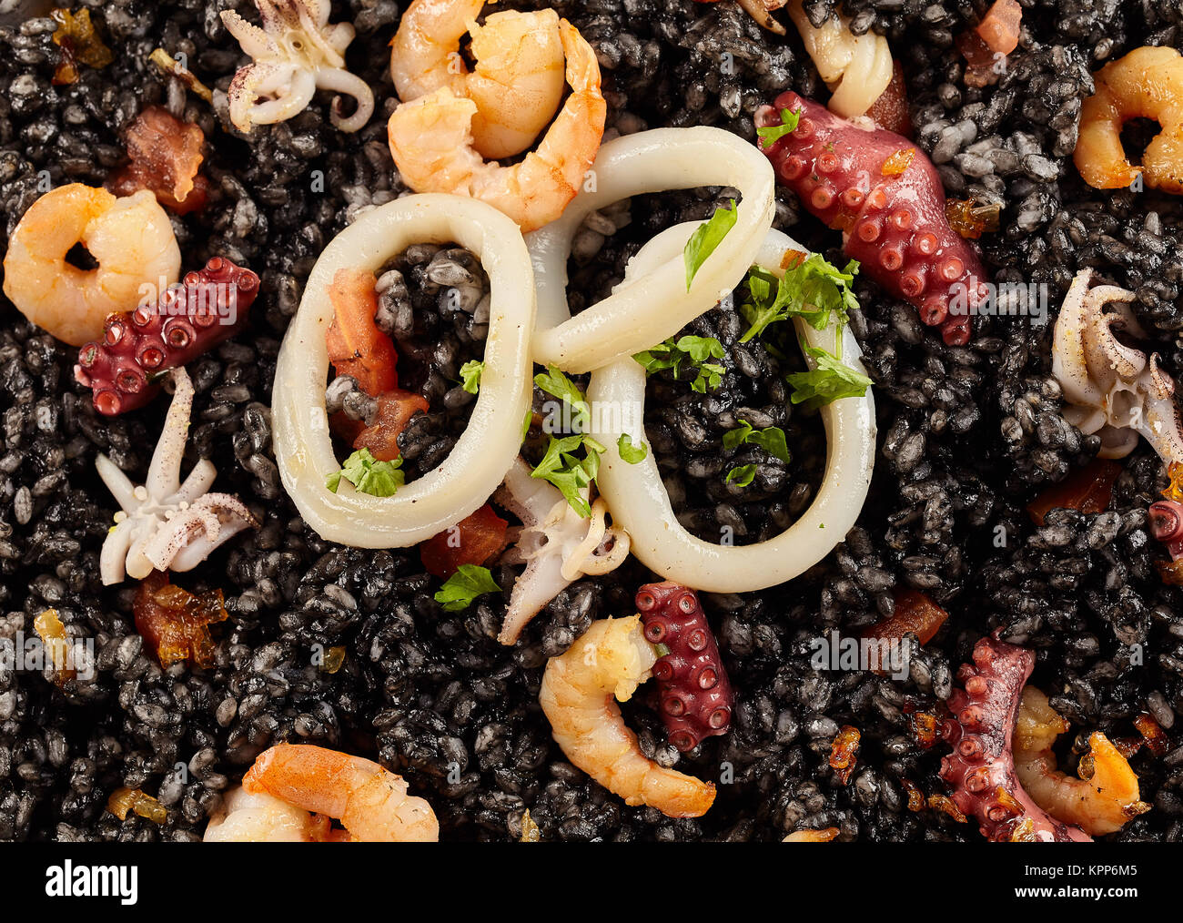Top down close up of arroz negro seafood dish, garnished with squid and ...