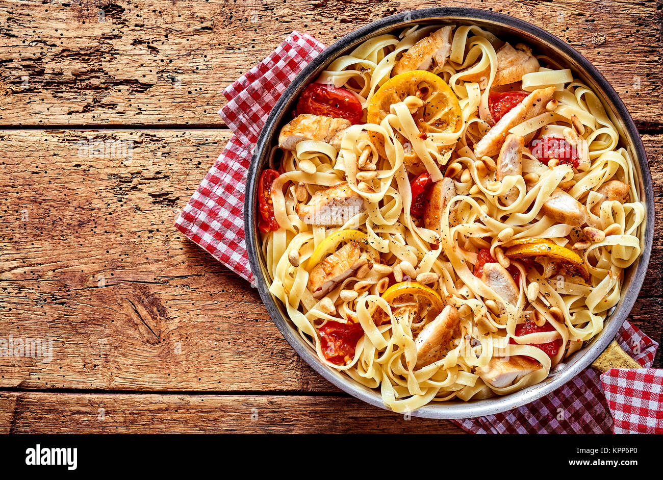 Top down view on round steel pan full of freshly cooked tomatoes, lemon ...