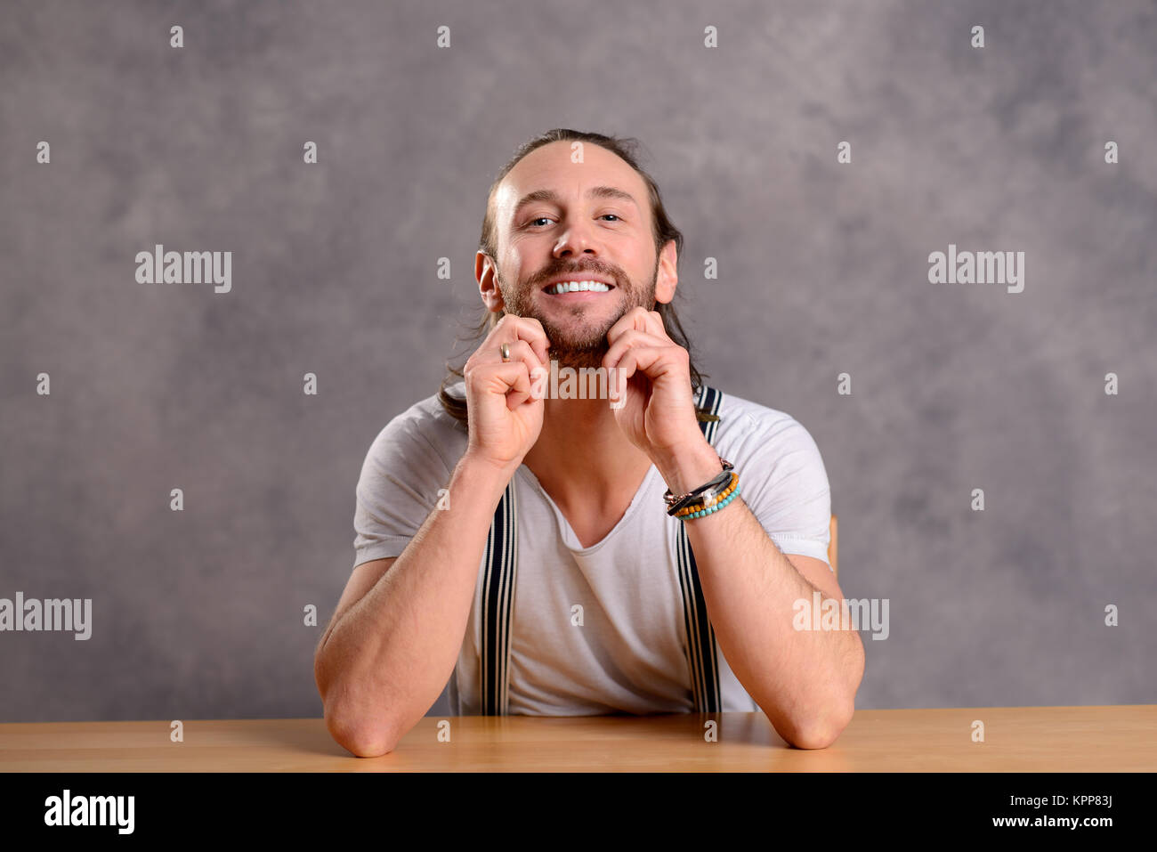 young man in front of gray background looking friendly in to the camera ...