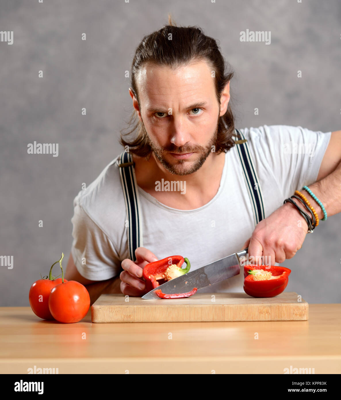 young bearded man cutting sweet pepper and looking angry Stock Photo ...