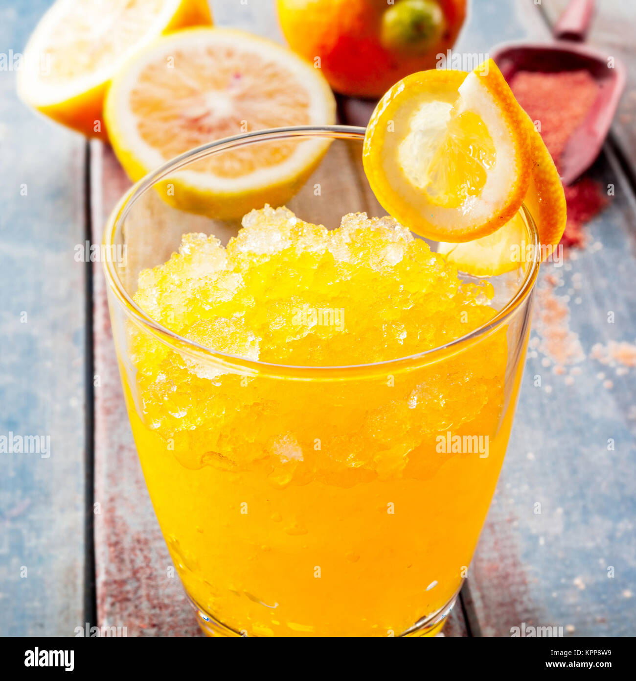 Single glass full of yellow lemon flavor beverage and peel with fruit and sugar scoop in ...