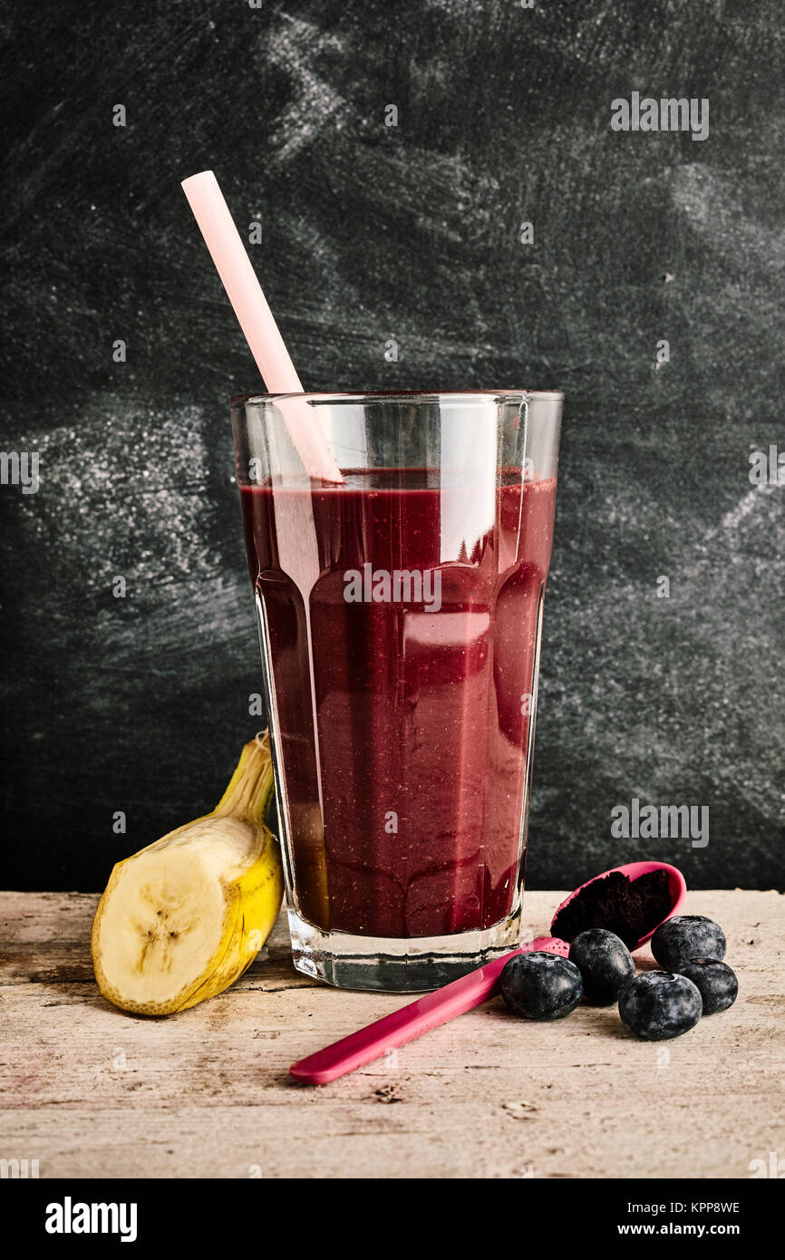 Single tall glass of delicious acai berry smoothie in between a slice ...
