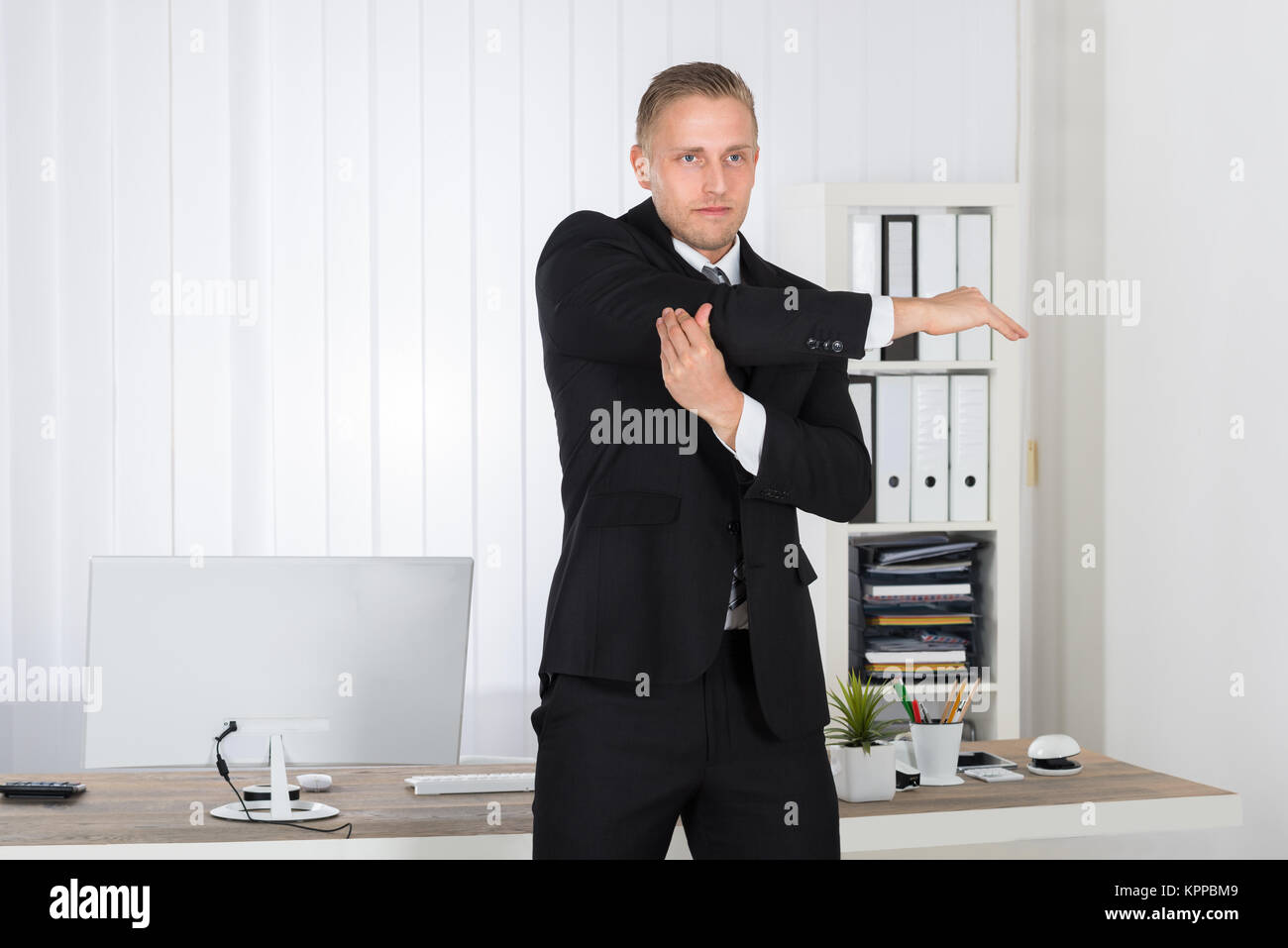 Businessman Stretching In Office Stock Photo - Alamy