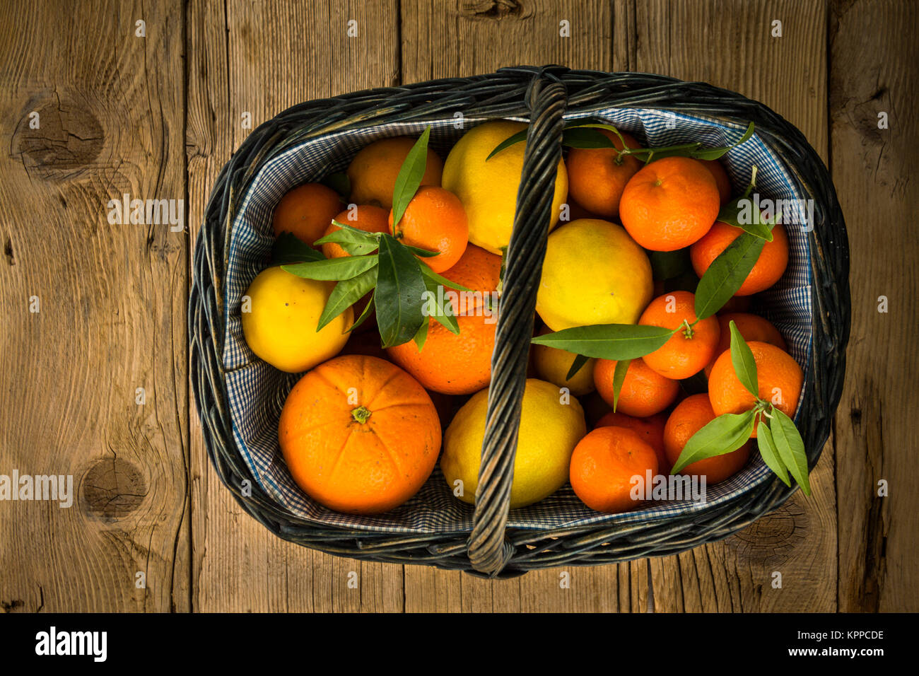 Various fresh citrus fruits in basket on old wooden background Stock ...