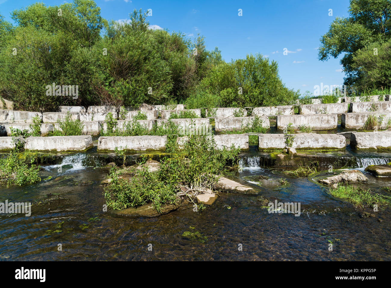 A Concrete blocks lying on a small river - dam Stock Photo - Alamy