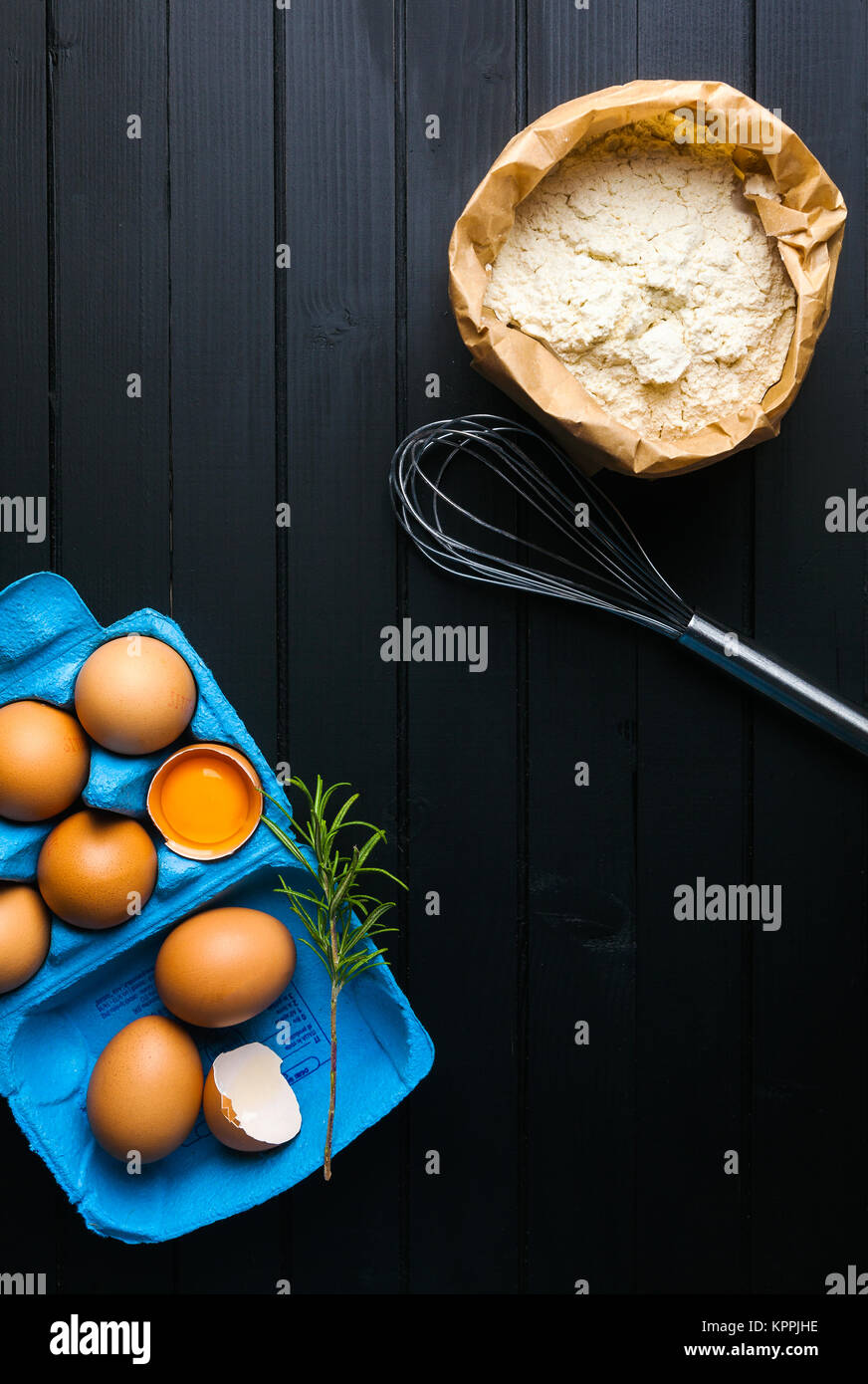 eggs in a blue paper container , flour and cooking utensils for baking ...