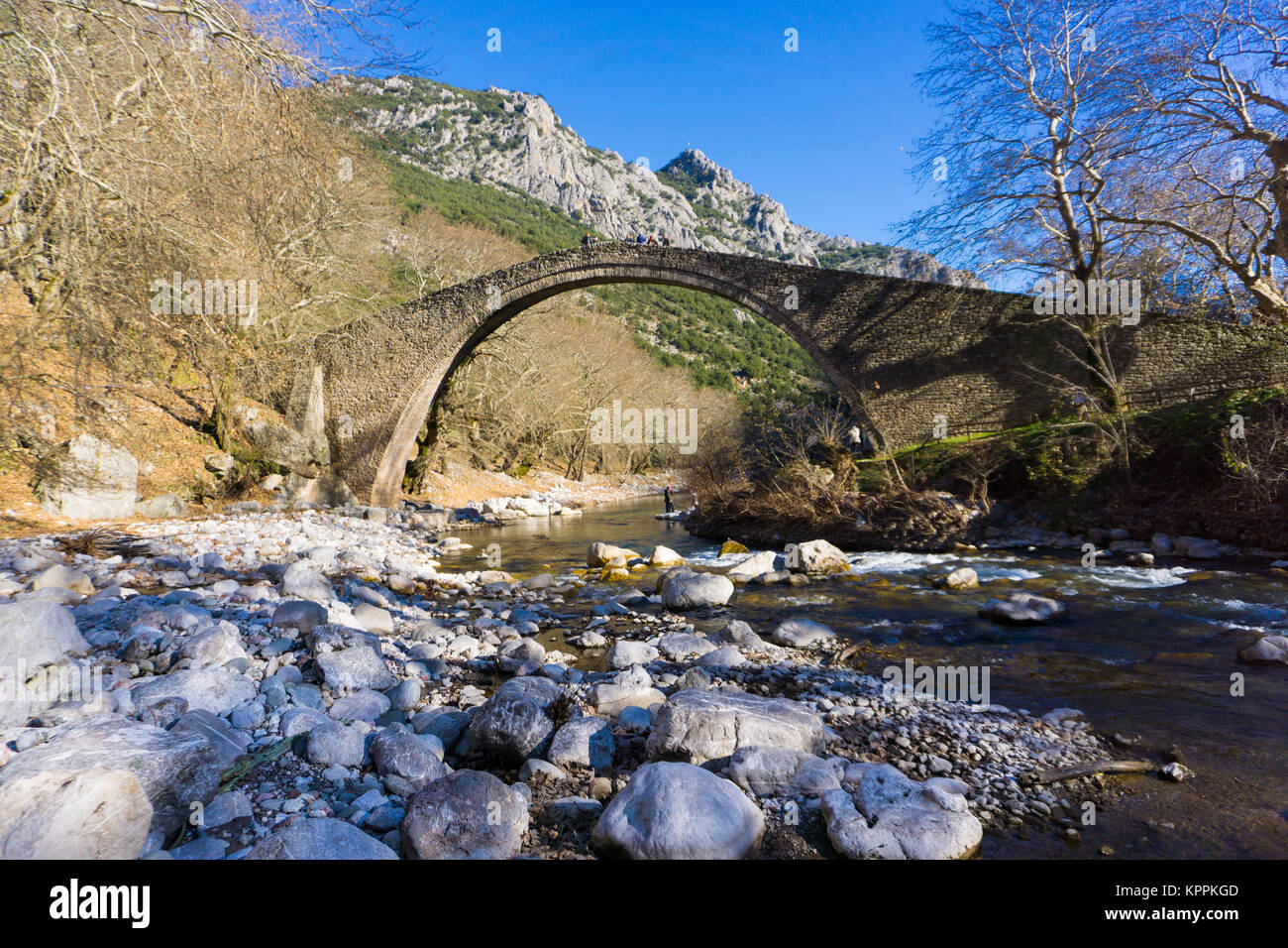 View of a stone arch bridge where people can walk on it through a paved ...