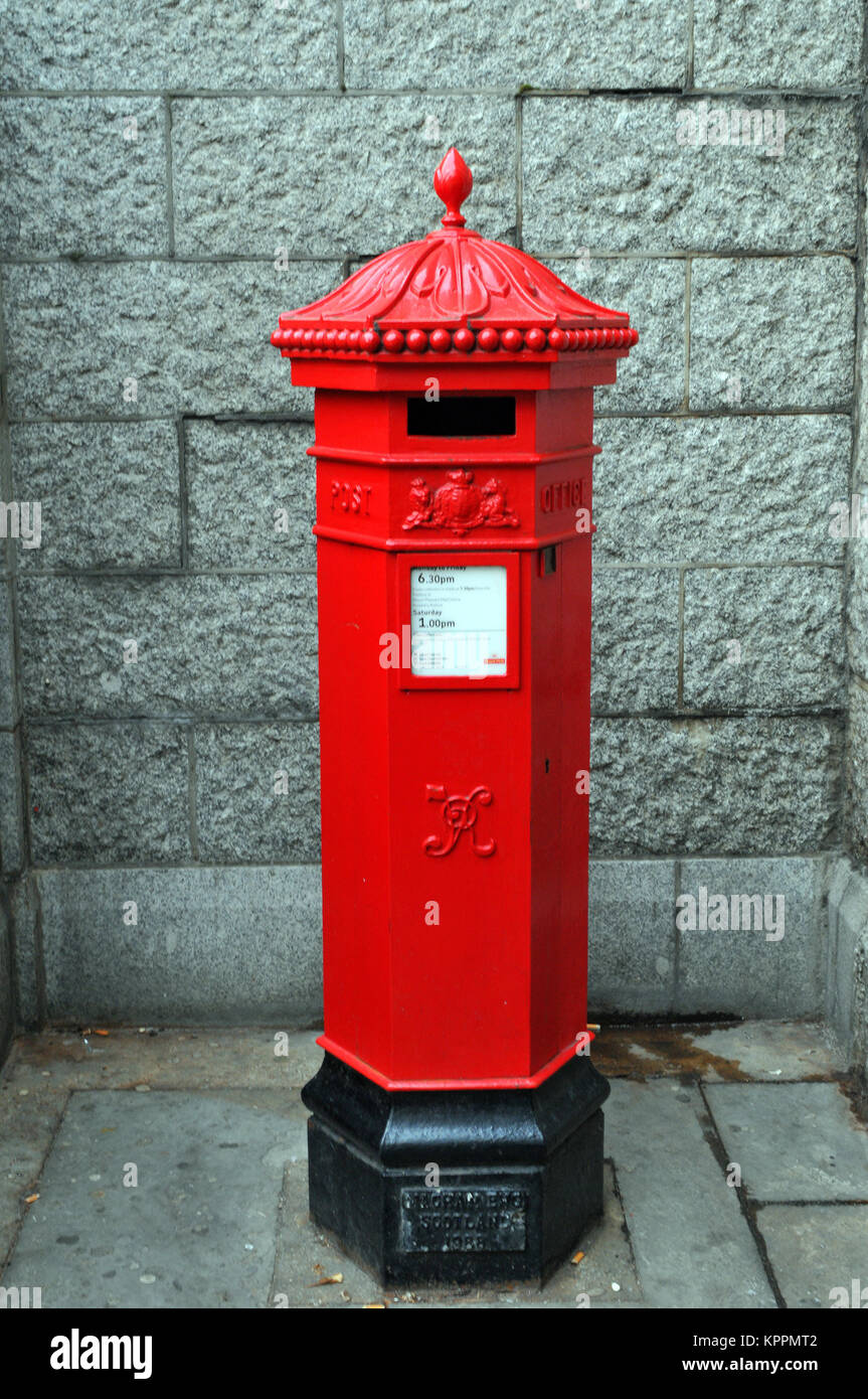 A traditional red pillar box operated by the Royal Mail with a finial ...