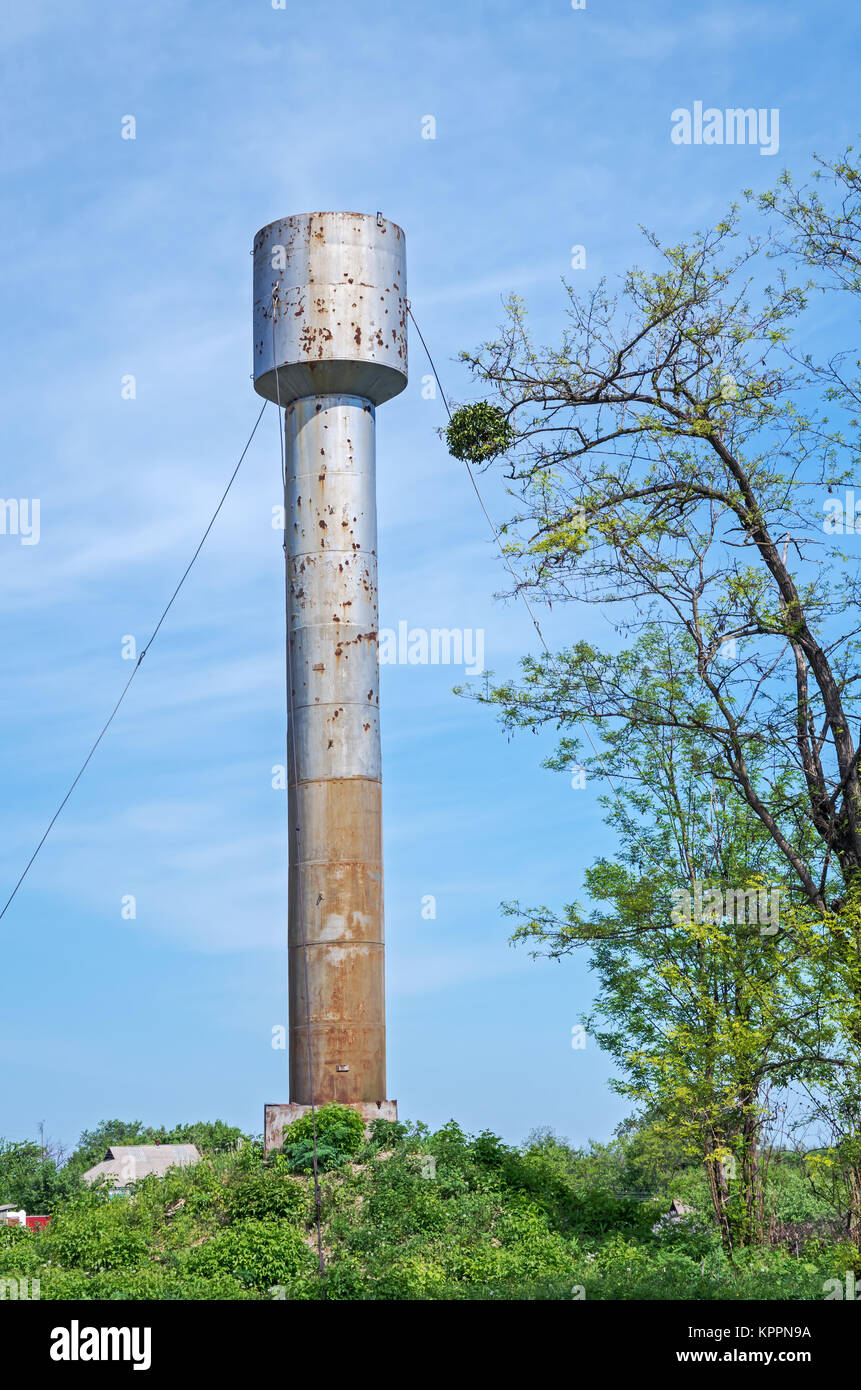 Old gray rustic metallic water tower on the top of a hill on the ...
