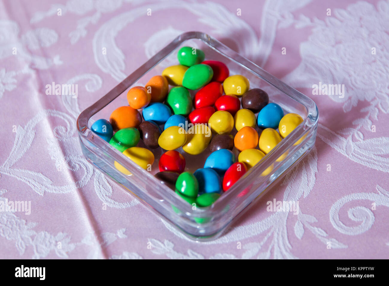 Multi colored sweets . Colored candy in a glass . Round chocolate is ...
