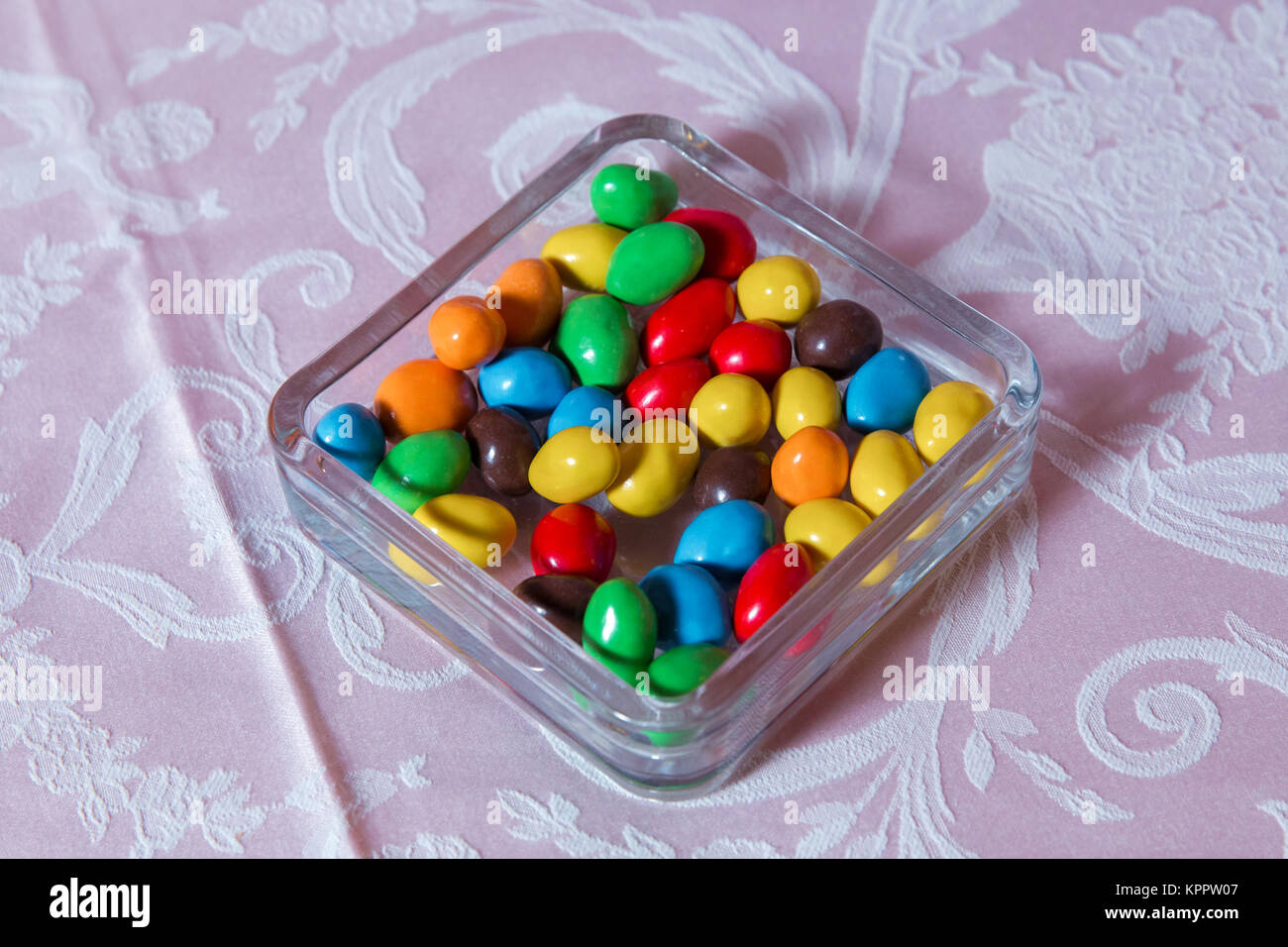 Multi colored sweets . Colored candy in a glass . Round chocolate is ...