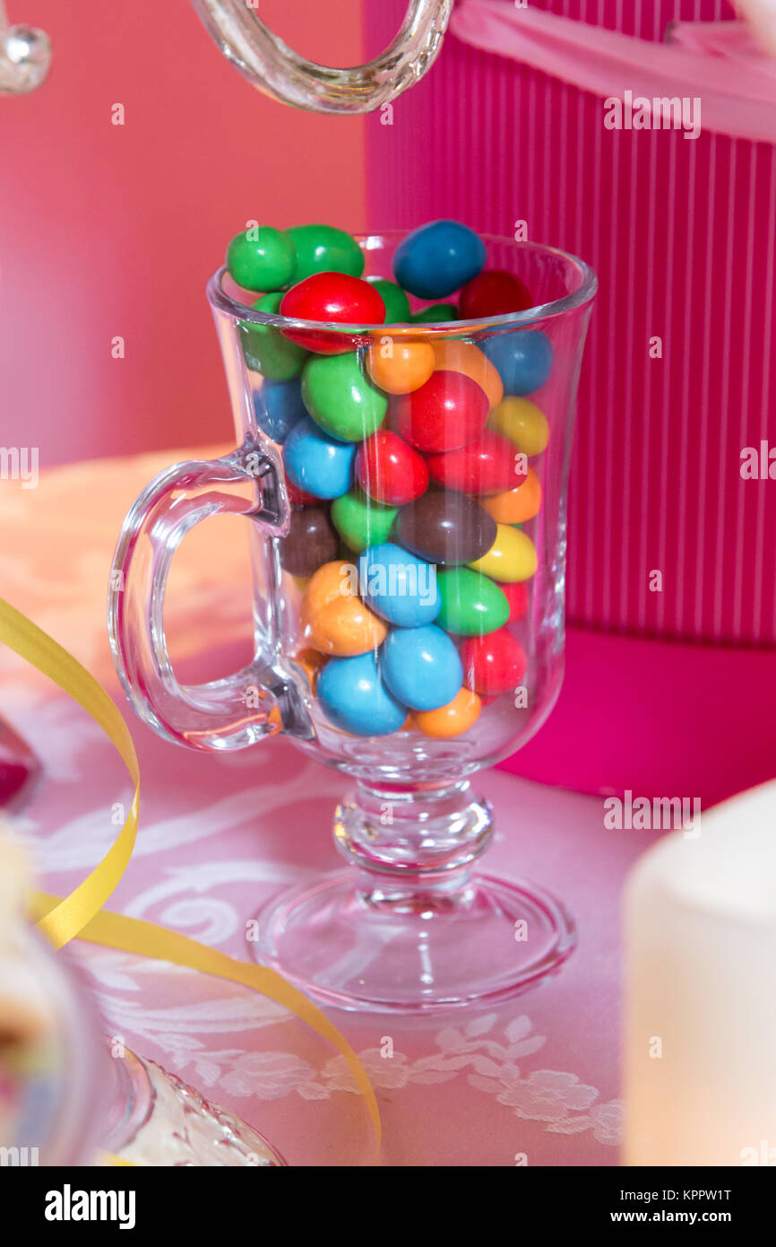 Multi colored sweets . Colored candy in a glass . Round chocolate is ...
