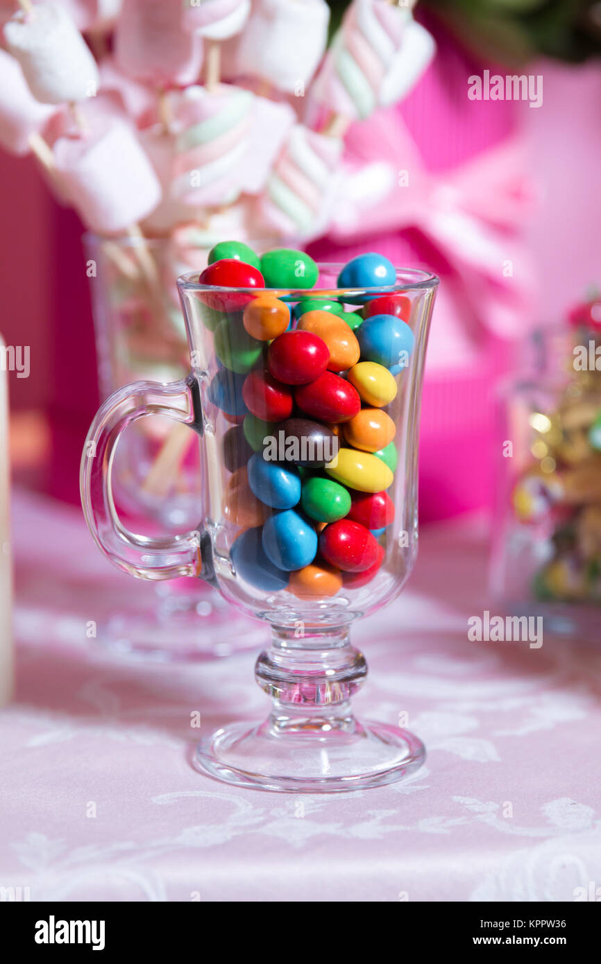 Multi colored sweets . Colored candy in a glass . Round chocolate is ...