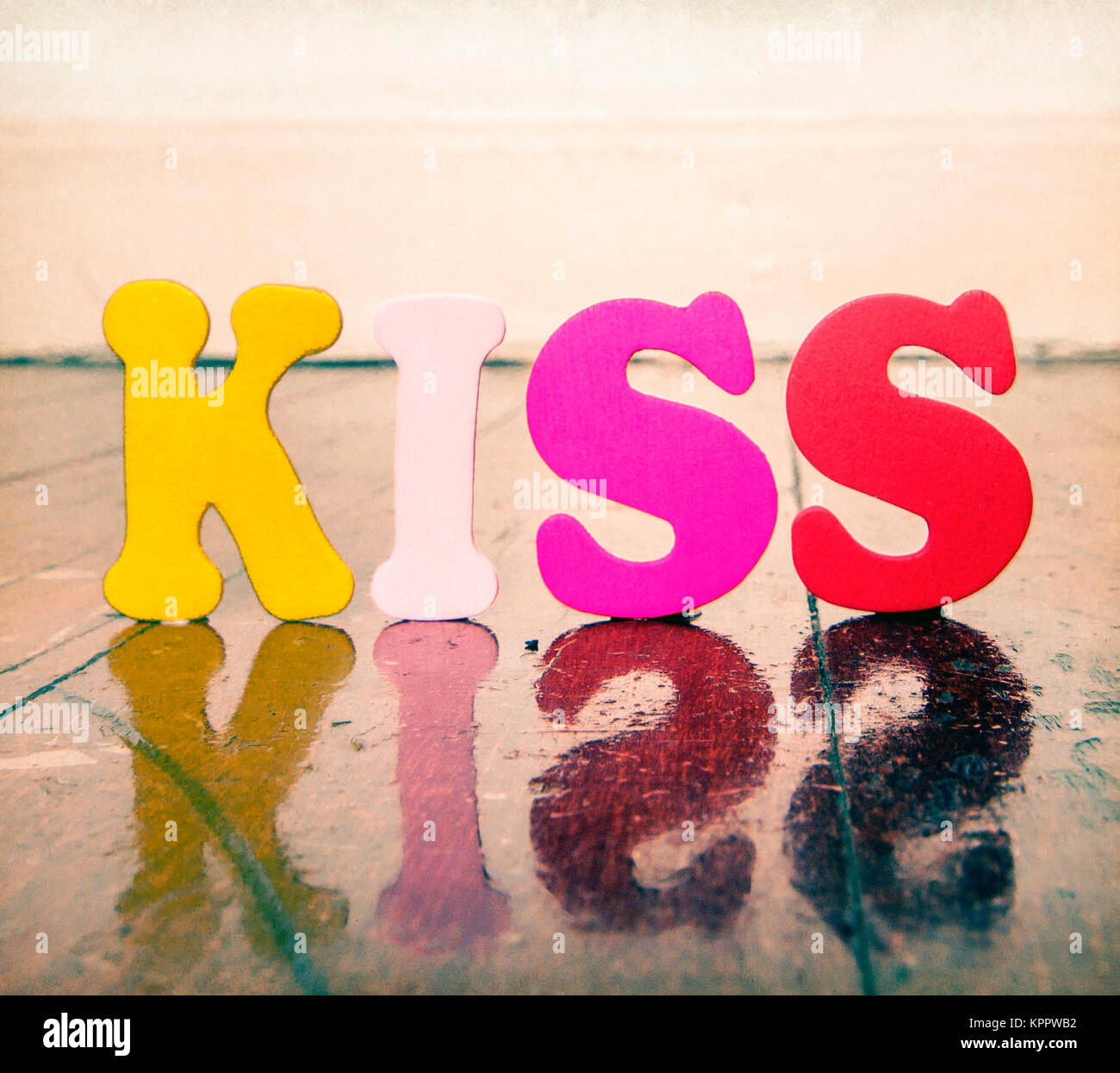 the word Kiss with color wooden letters on a wooden floor with ...