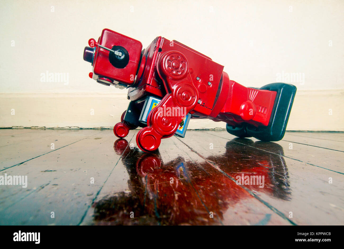 red retro robot toy doing push ups on an old wooden floor with ...