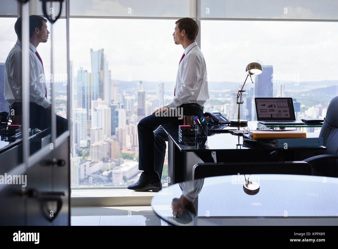 Business Person Sits On Desk Looking Out Of Office Window Stock Photo ...