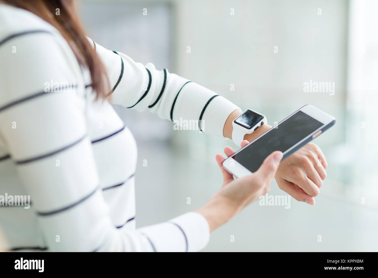 Woman connecting cellphone and smart watch Stock Photo - Alamy