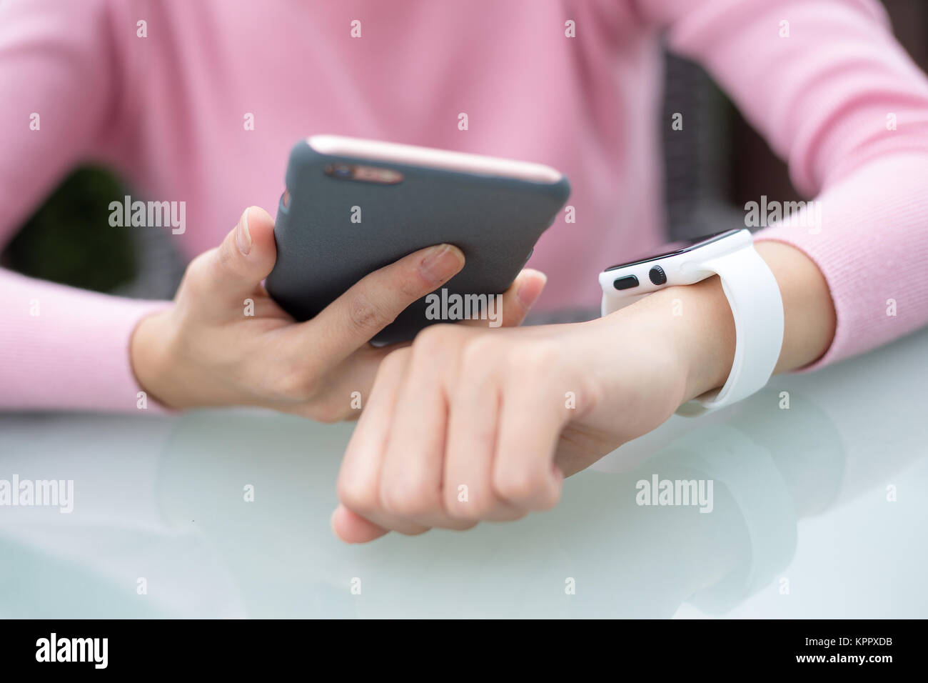 Woman using mobile phone to connect with smart watch Stock Photo - Alamy