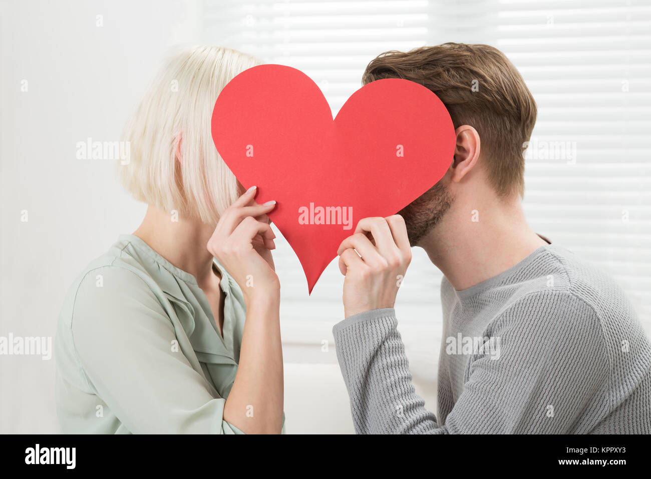 Young Couple Kissing Behind Heart Shape Stock Photo - Alamy