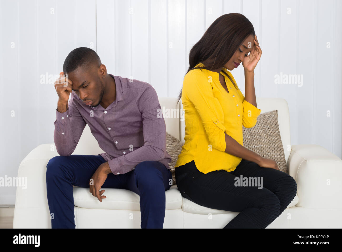Couple Sitting Back To Back On Sofa Stock Photo - Alamy