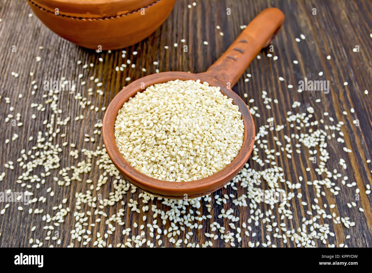 Sesame seeds in clay ladle on board Stock Photo - Alamy