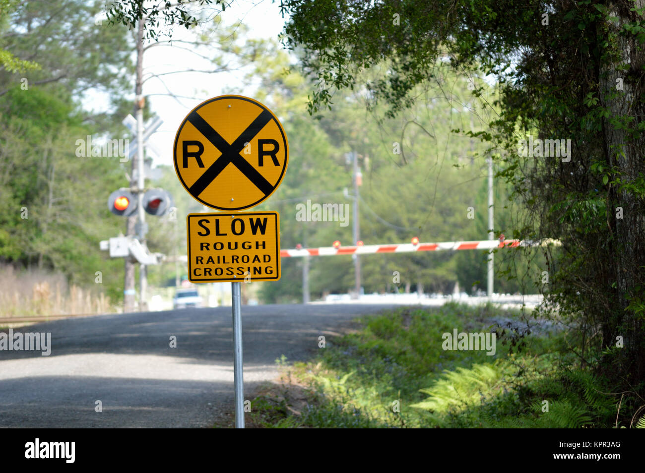 Slow Rough Railroad Crossing sign with railroad crossing in background ...