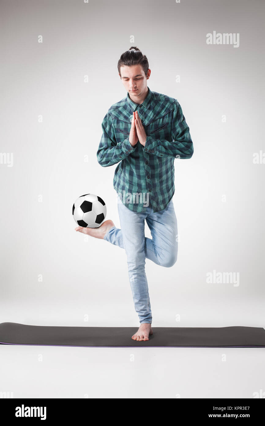Portrait of young man, practicing yoga with football ball Stock Photo ...