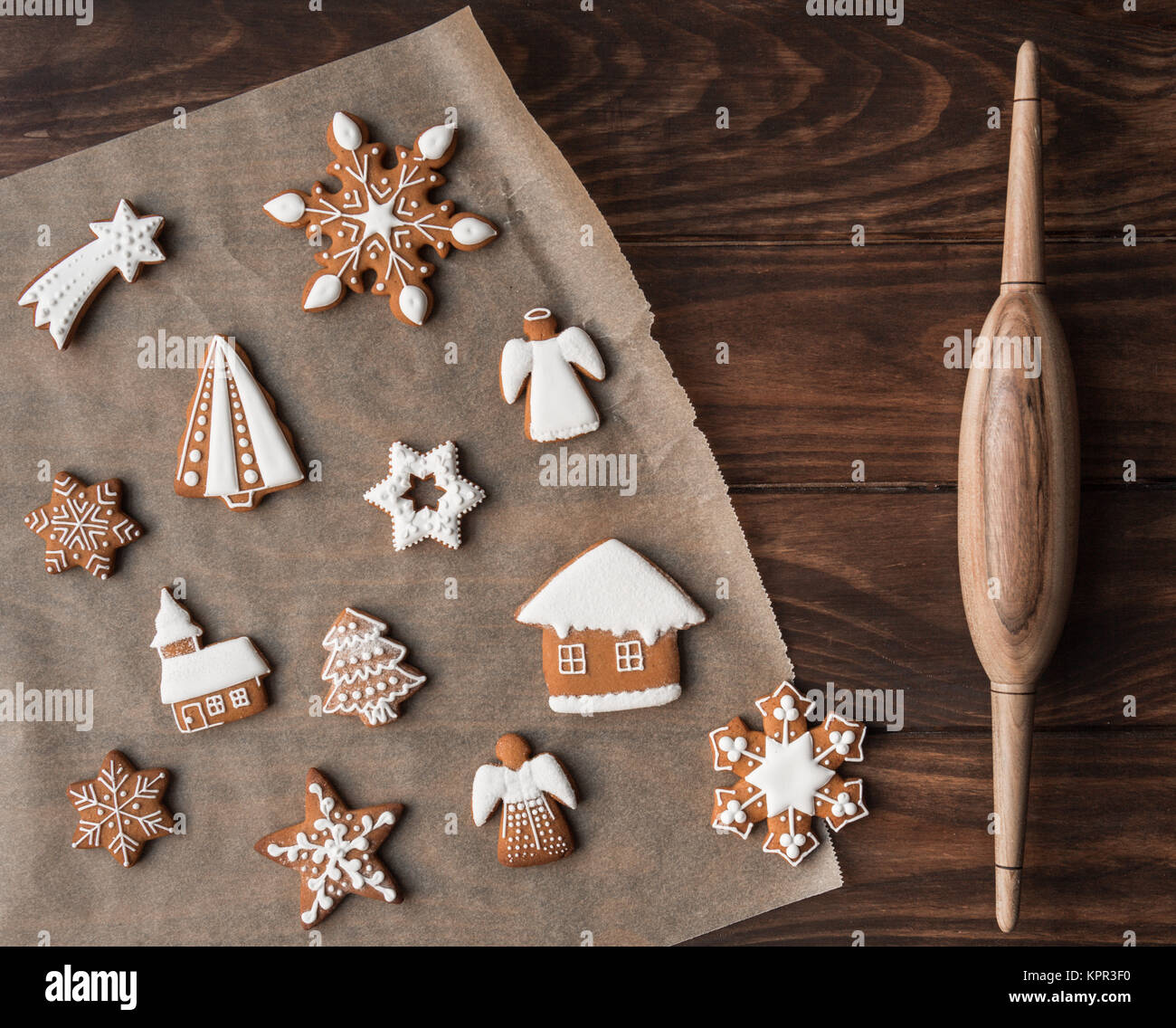 Christmas decorated gingerbread cookies on cooking paper over old brown ...