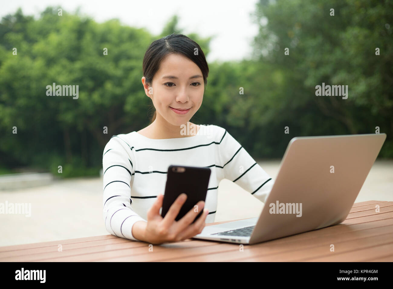 Woman use of cellphone and laptop computer Stock Photo - Alamy