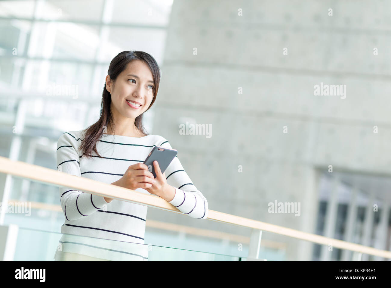 Woman using mobile phone and standing at indoor Stock Photo - Alamy