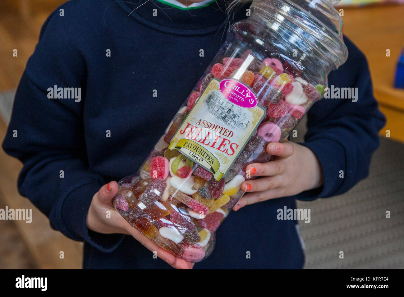 Child holding a large plastic jar of assorted jellies Stock Photo - Alamy
