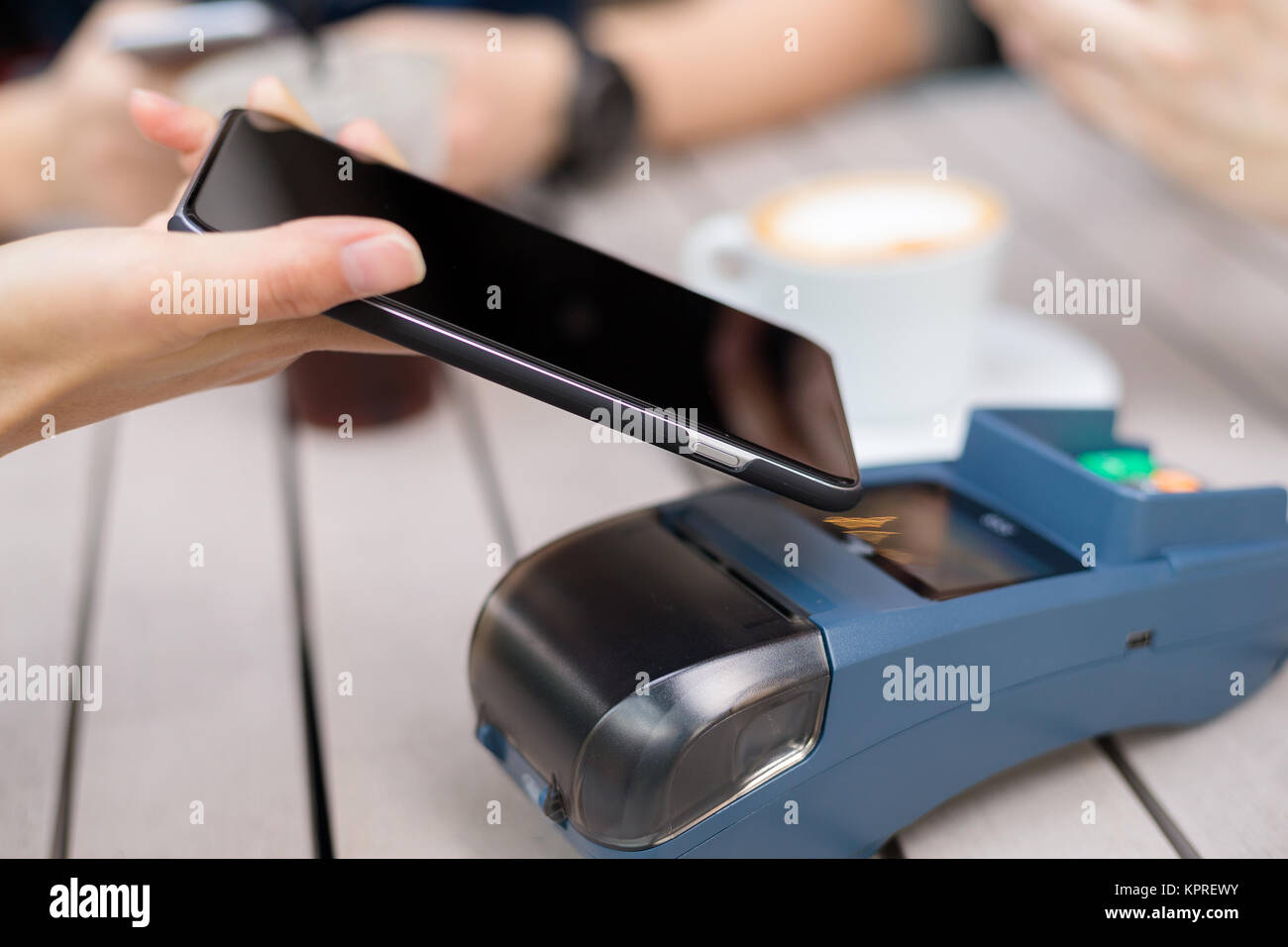 Friend using cellphone to pay Stock Photo - Alamy