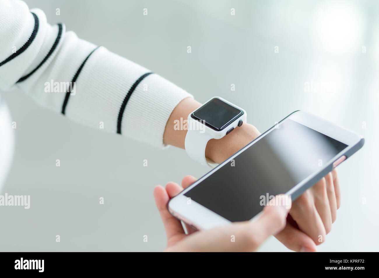 Woman connecting smartwatch and mobile phone Stock Photo - Alamy