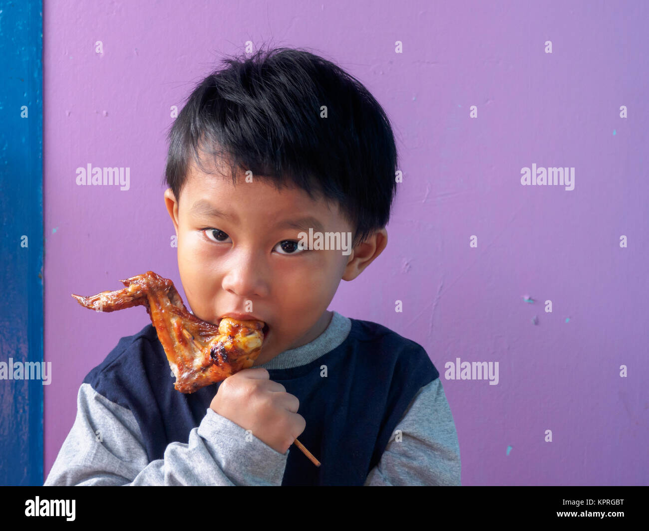 asian boy eating roasted chicken wing Stock Photo - Alamy