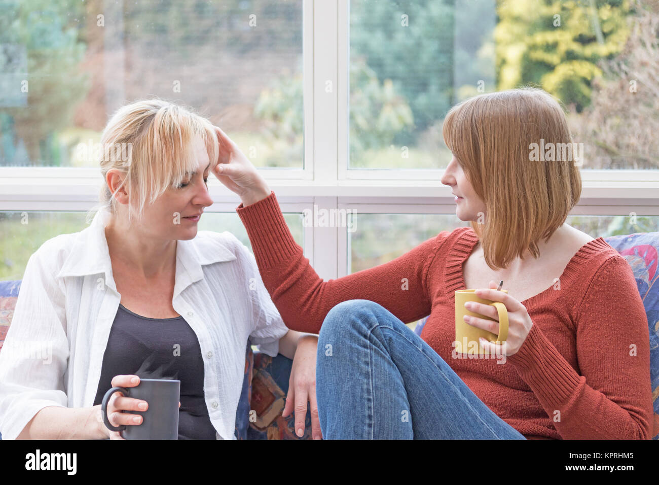 Young woman is touching the head of the other woman Stock Photo - Alamy