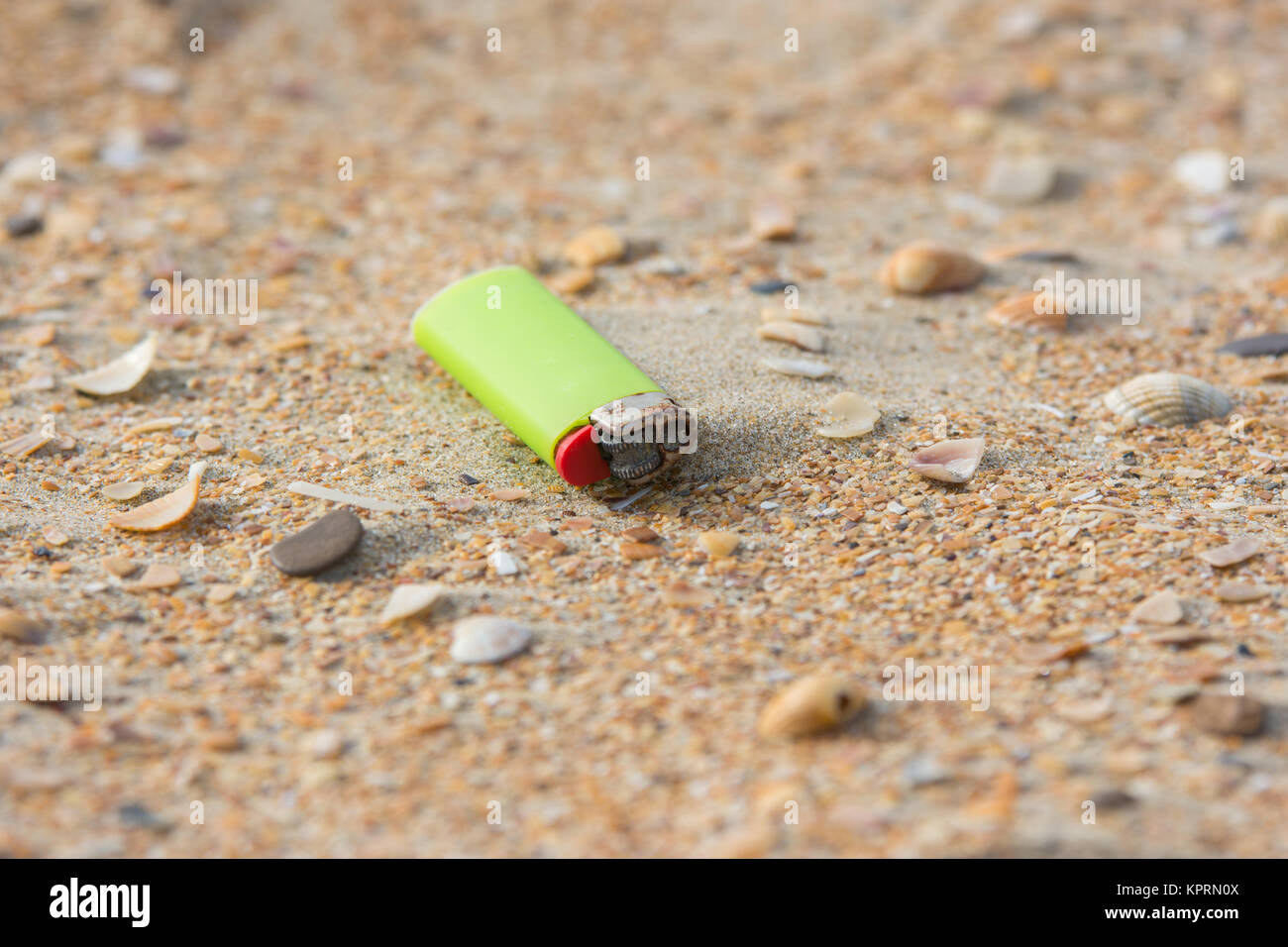 Old used lighter in the sand on the beach Stock Photo - Alamy