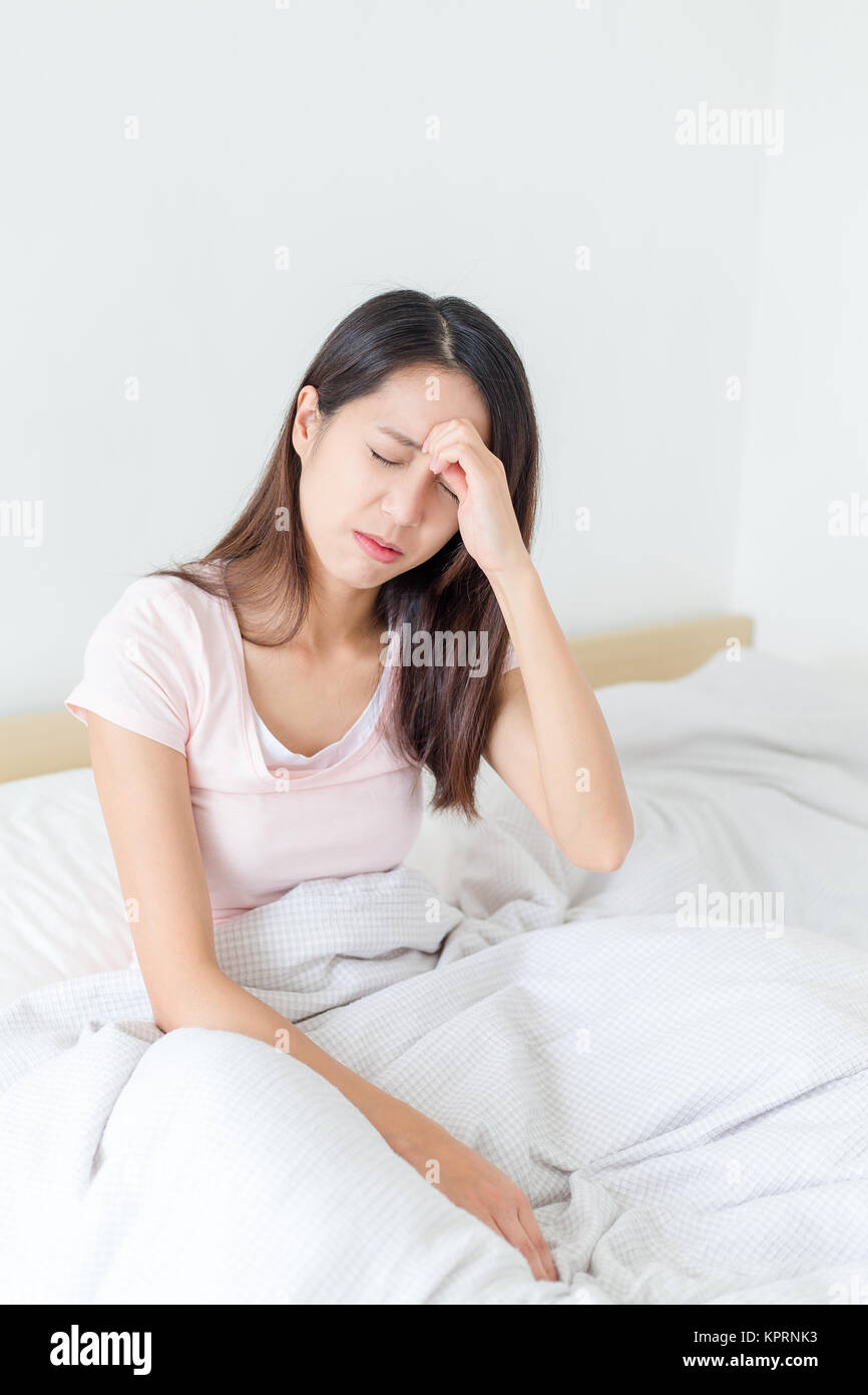 Woman feeling dizzy and sitting on bed Stock Photo - Alamy