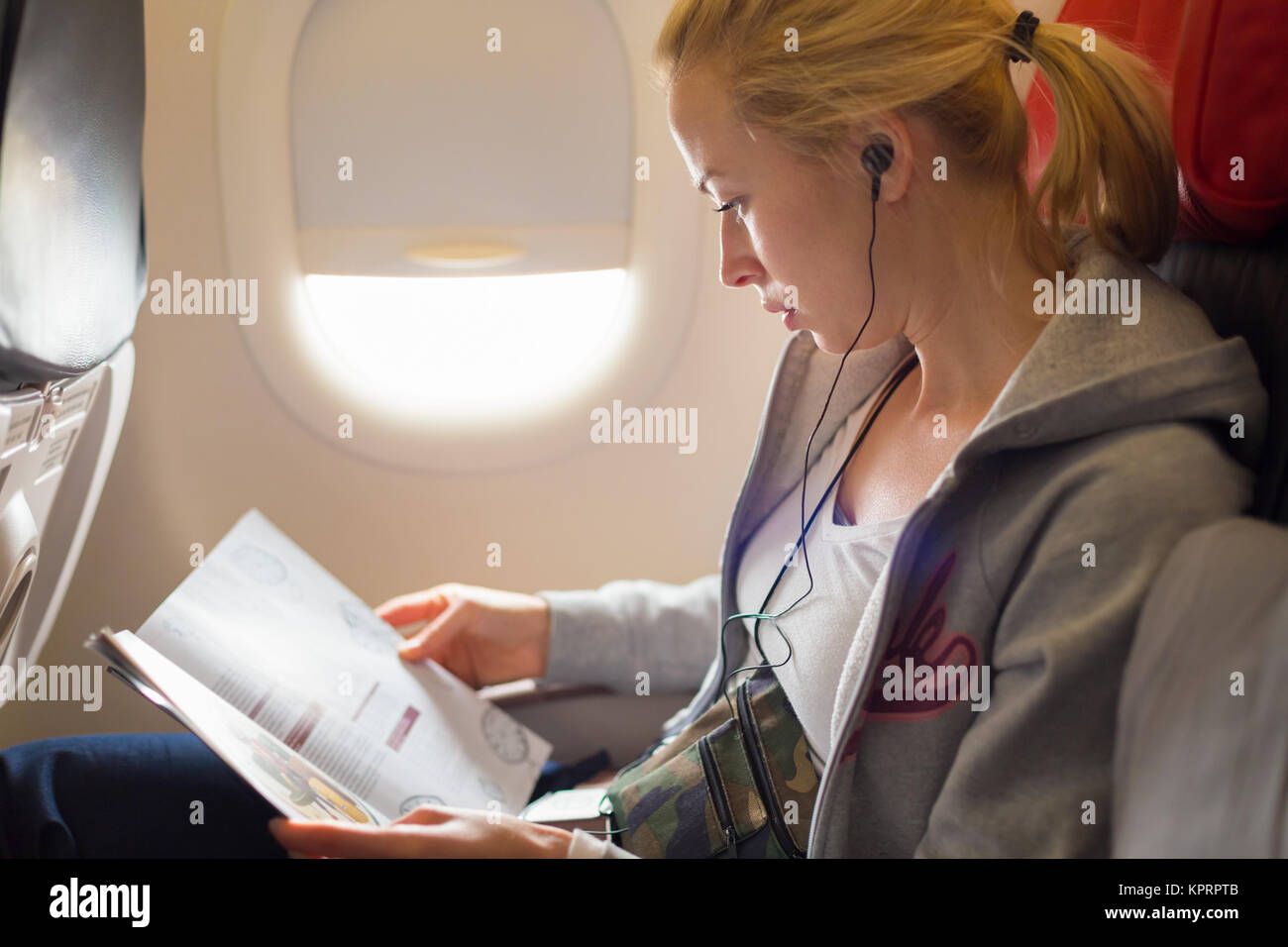 Woman reading magazine on airplane Stock Photo - Alamy