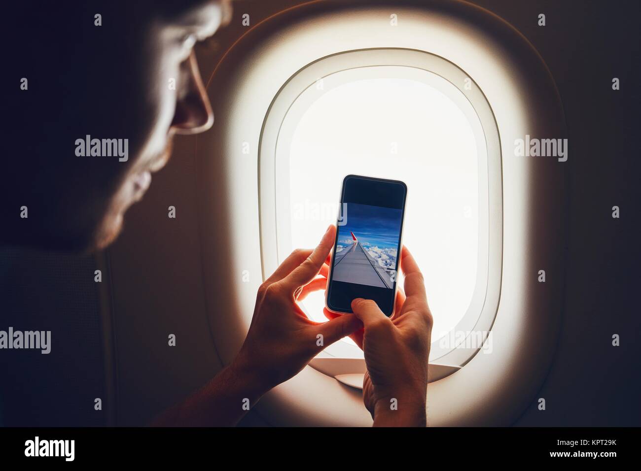 Young passenger taking photo from the window of the airplane during ...