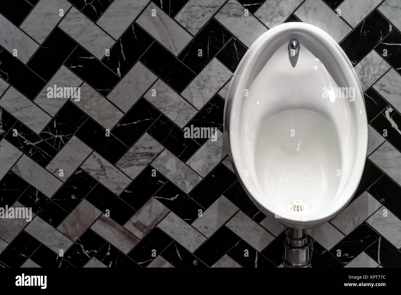 Single white male urinal in white porcelain with a tiled pattern in ...