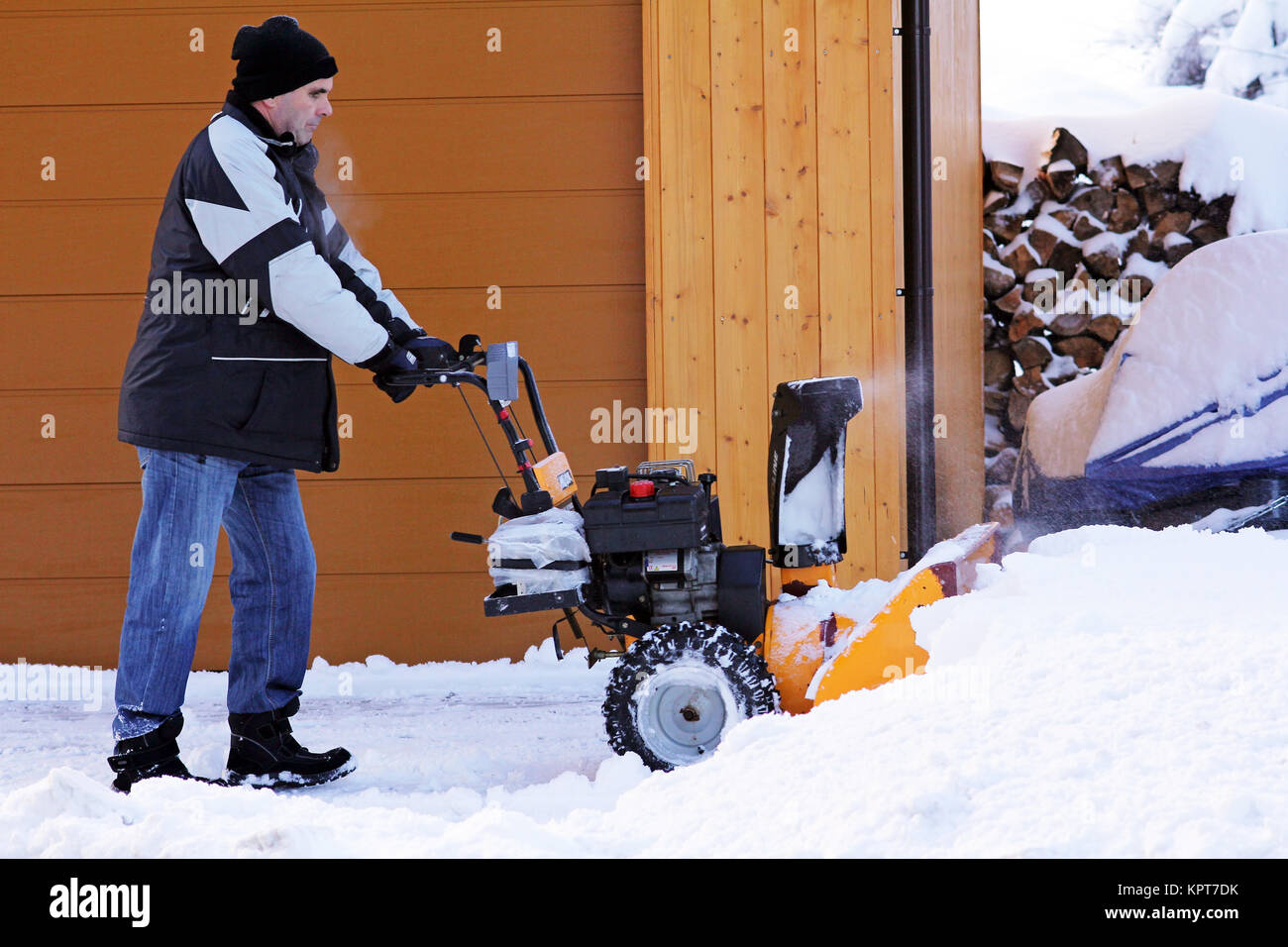 a man uses a snowblower to clear snow in front of a driveway Stock ...