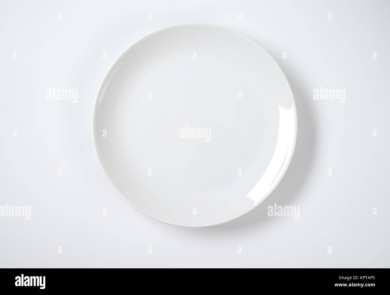 empty rimless white plate on off-white background Stock Photo - Alamy
