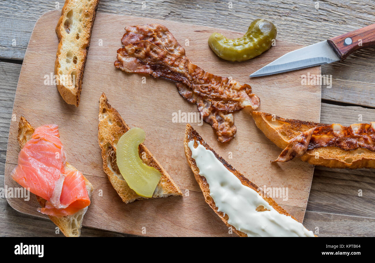 Toasts with different toppings on the wooden board Stock Photo - Alamy