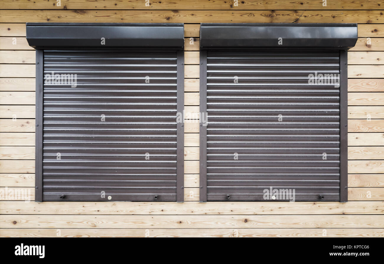 Wooden wall with two windows protected with roller shutters, background ...