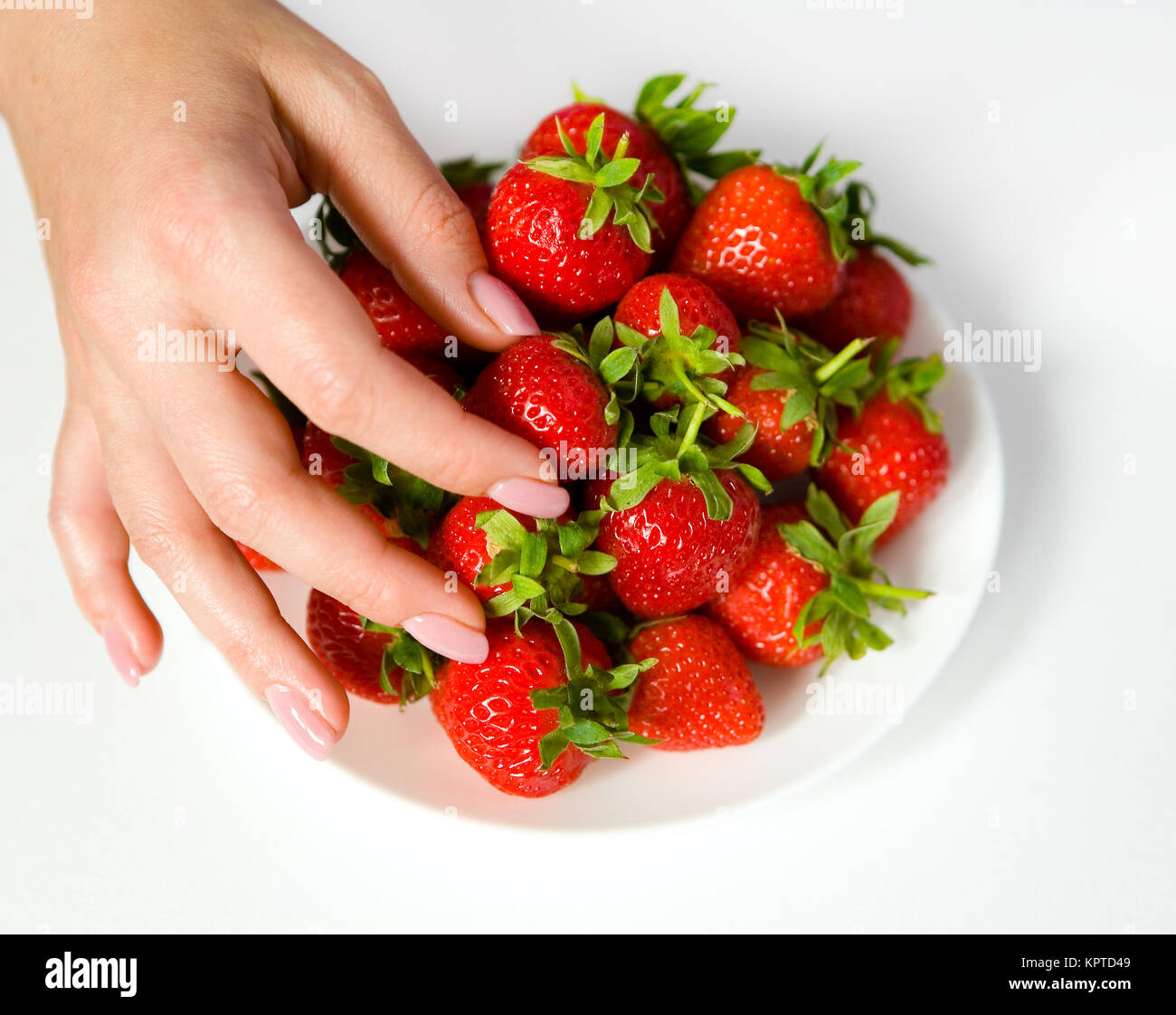 Beautiful female fingers with a manicure take a strawberry berry from ...