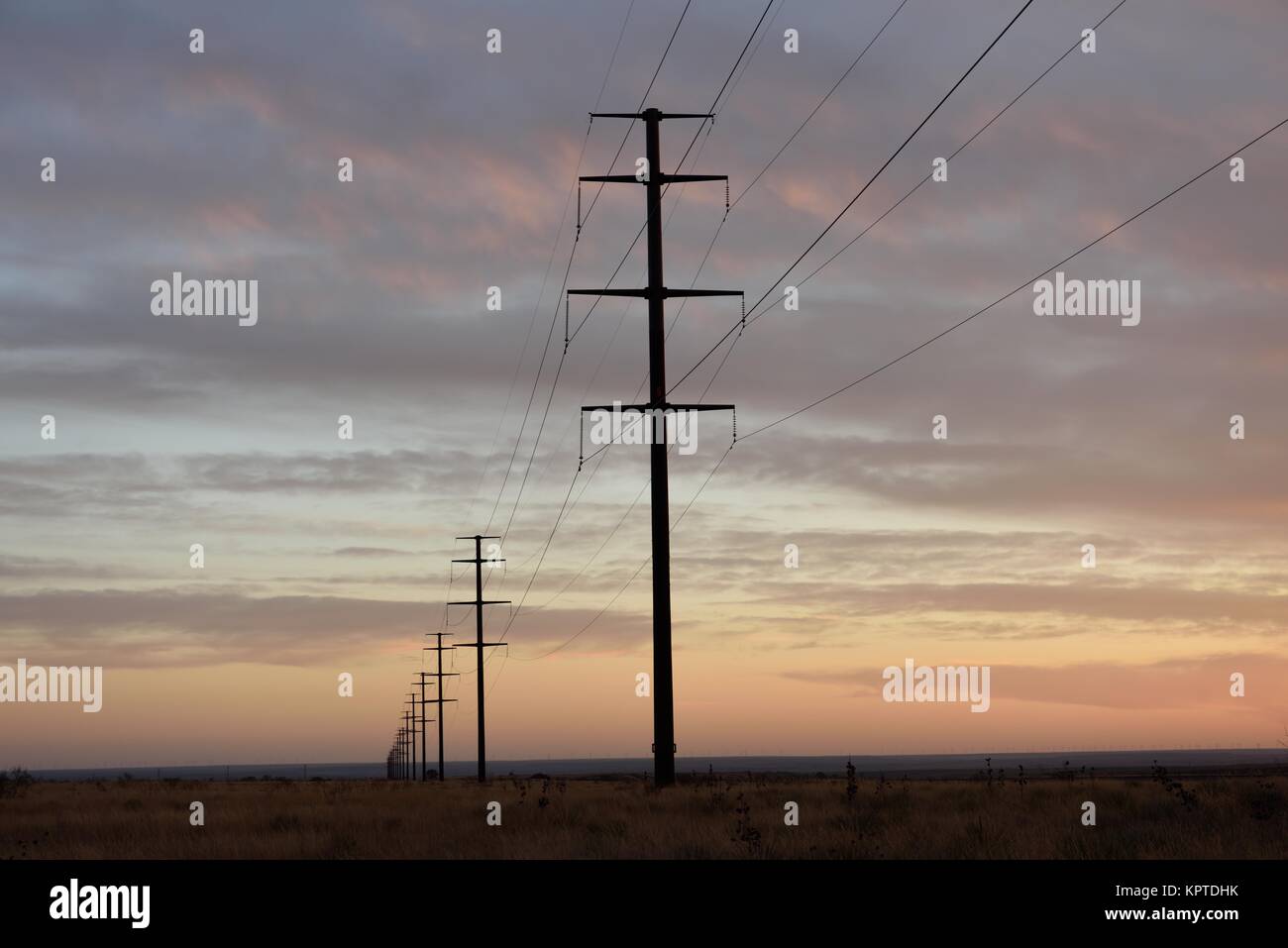 Long row of tall steel electricity pylons and high voltage power lines ...