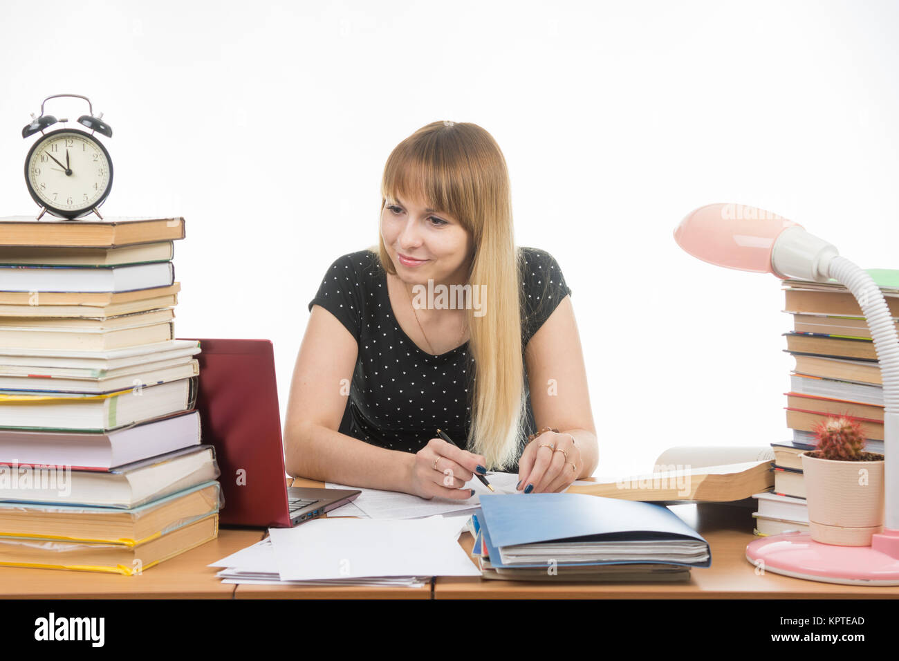 A student at a table littered with books in the library with a smile ...