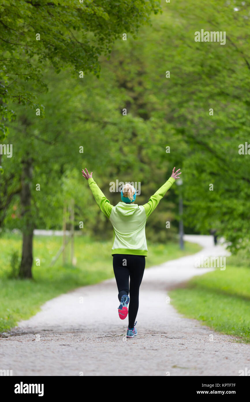 I have made it. Sporty young female runner arms rised in city park ...